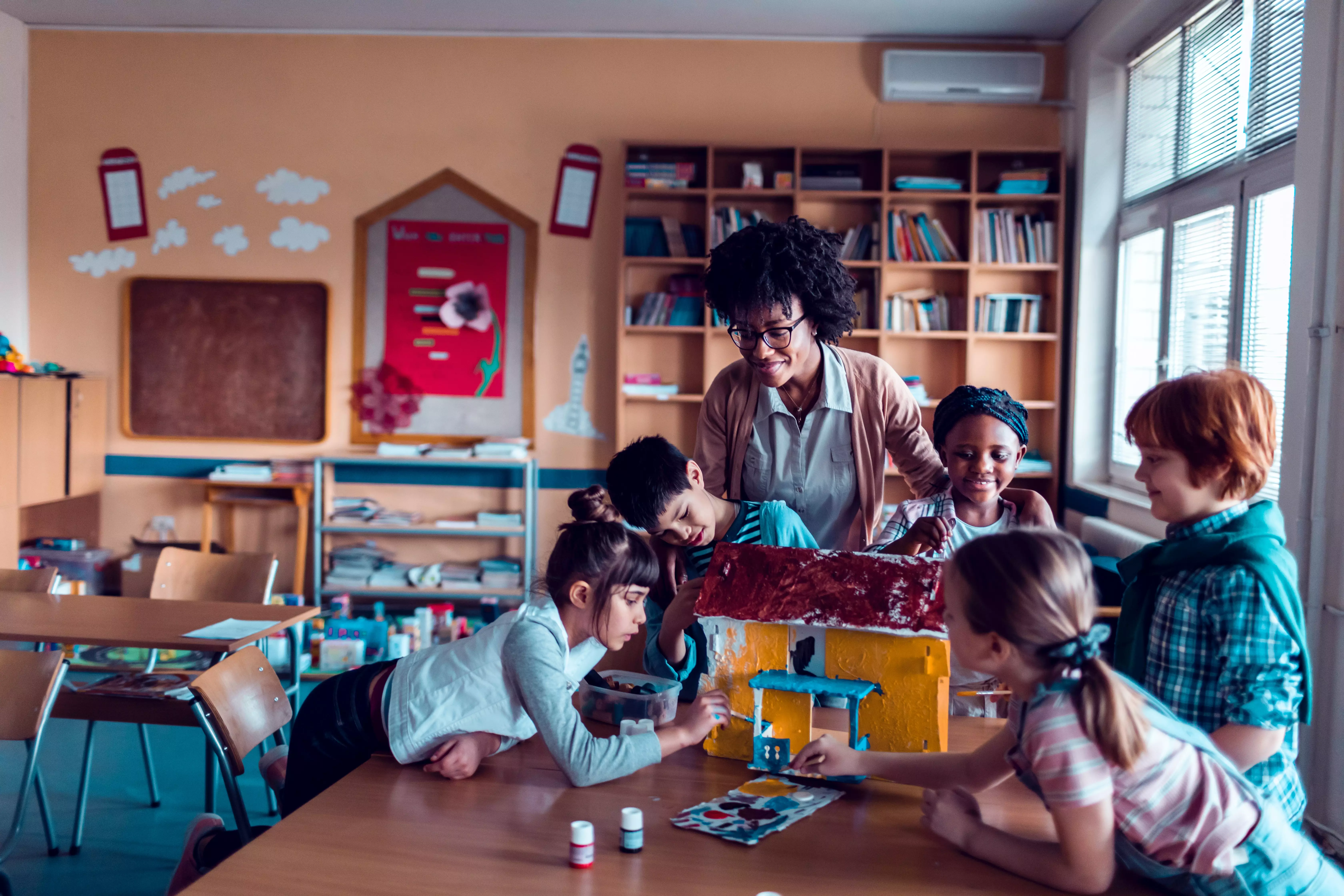 Close-up fan in groep basisskoallebern dy't in hûs skilderje mei har learaar tidens keunstklasse ...