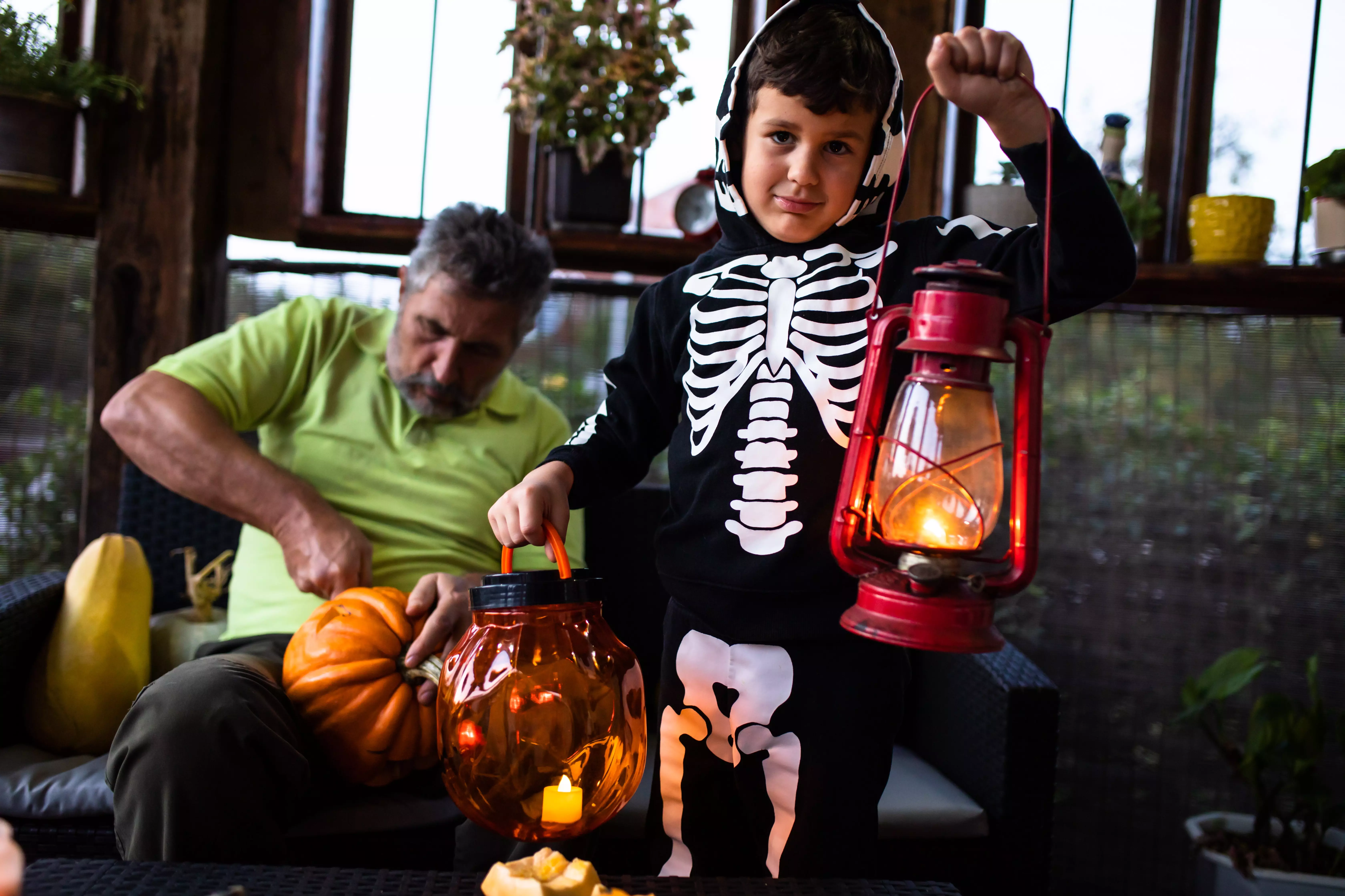 Isang cute na batang lalaki na naka-skeleton costume na may hawak na plastic na Halloween pumpkin, halloween jokes at riddles