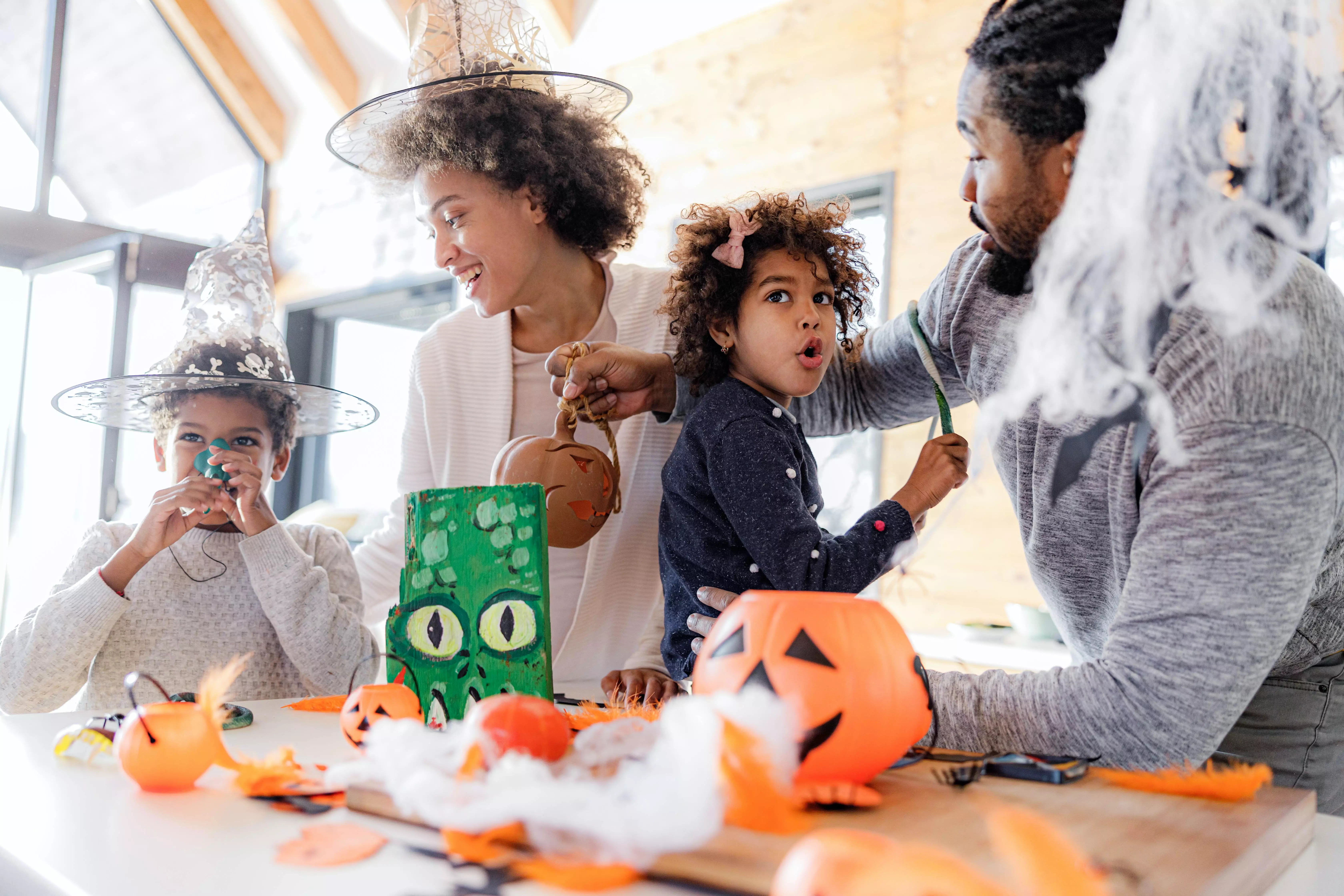 Boldog fekete szülők és gyerekeik otthon élvezik a Halloween ünneplést, a halloween kopog...