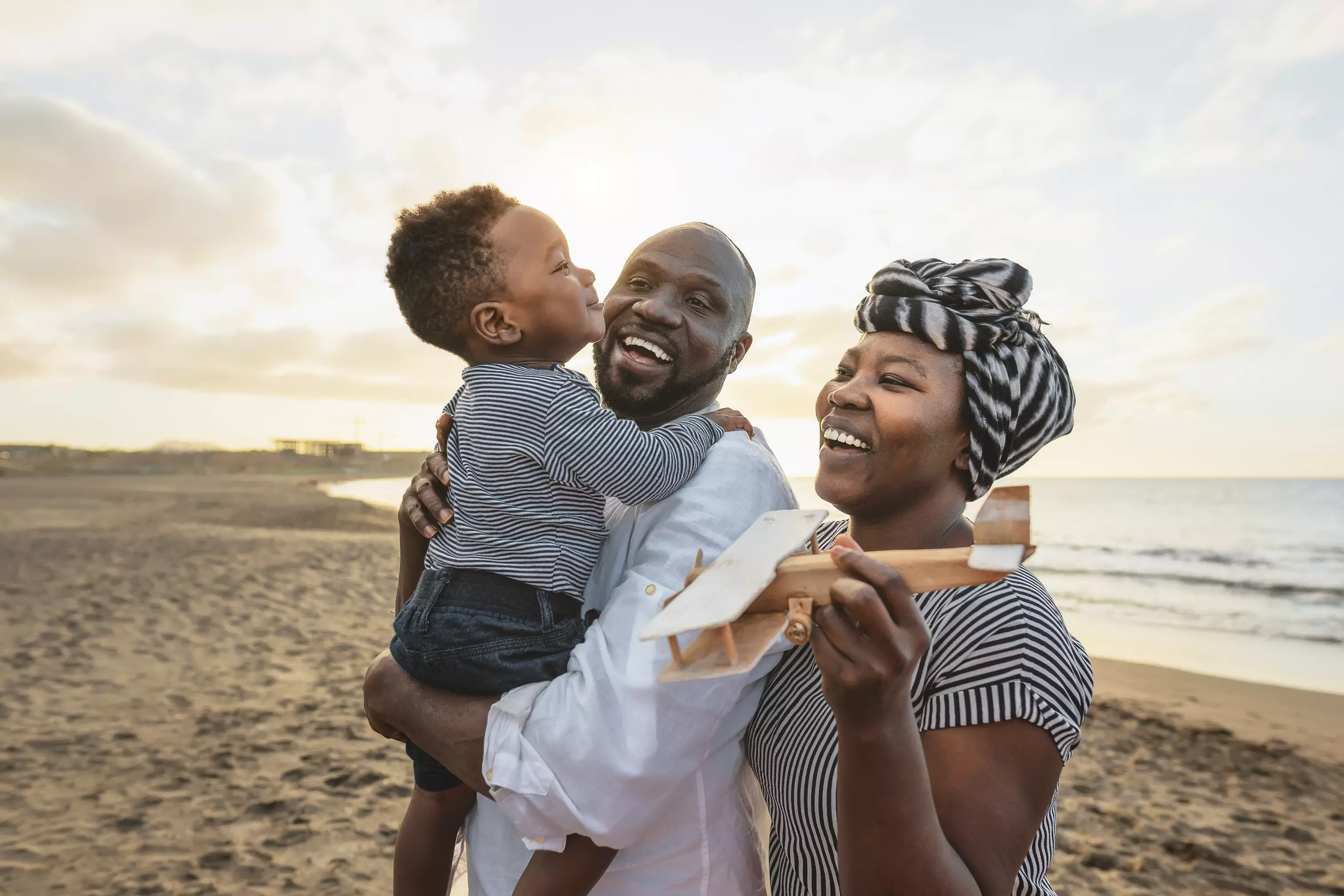 Glad afrikansk familie som har det gøy på stranden i sommerferien, sommer baby guttenavn