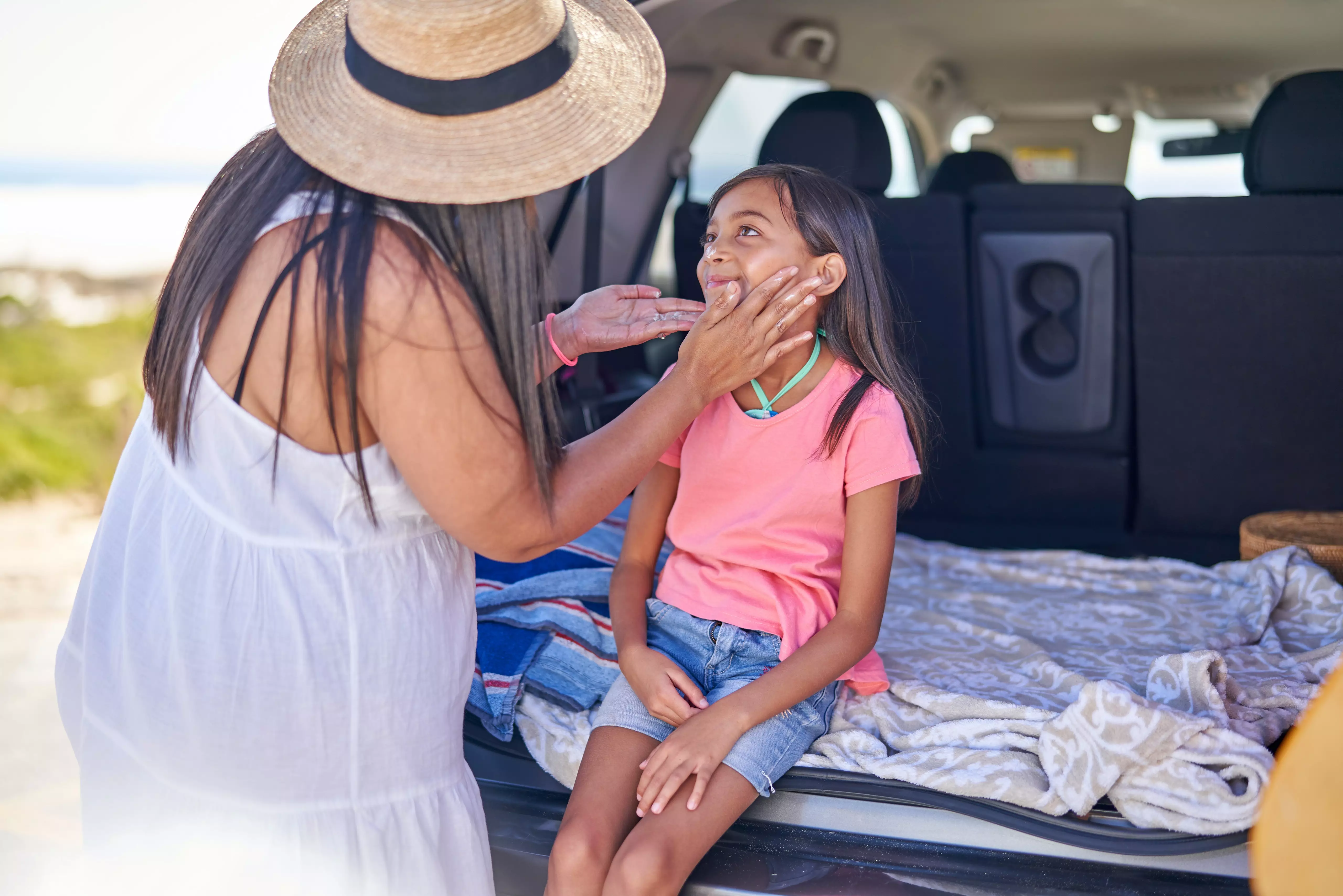 Dayika ku li pişta otomobîlê sunscreenê li ser çokên keça xwe dike, gelo sunscreen diqede?