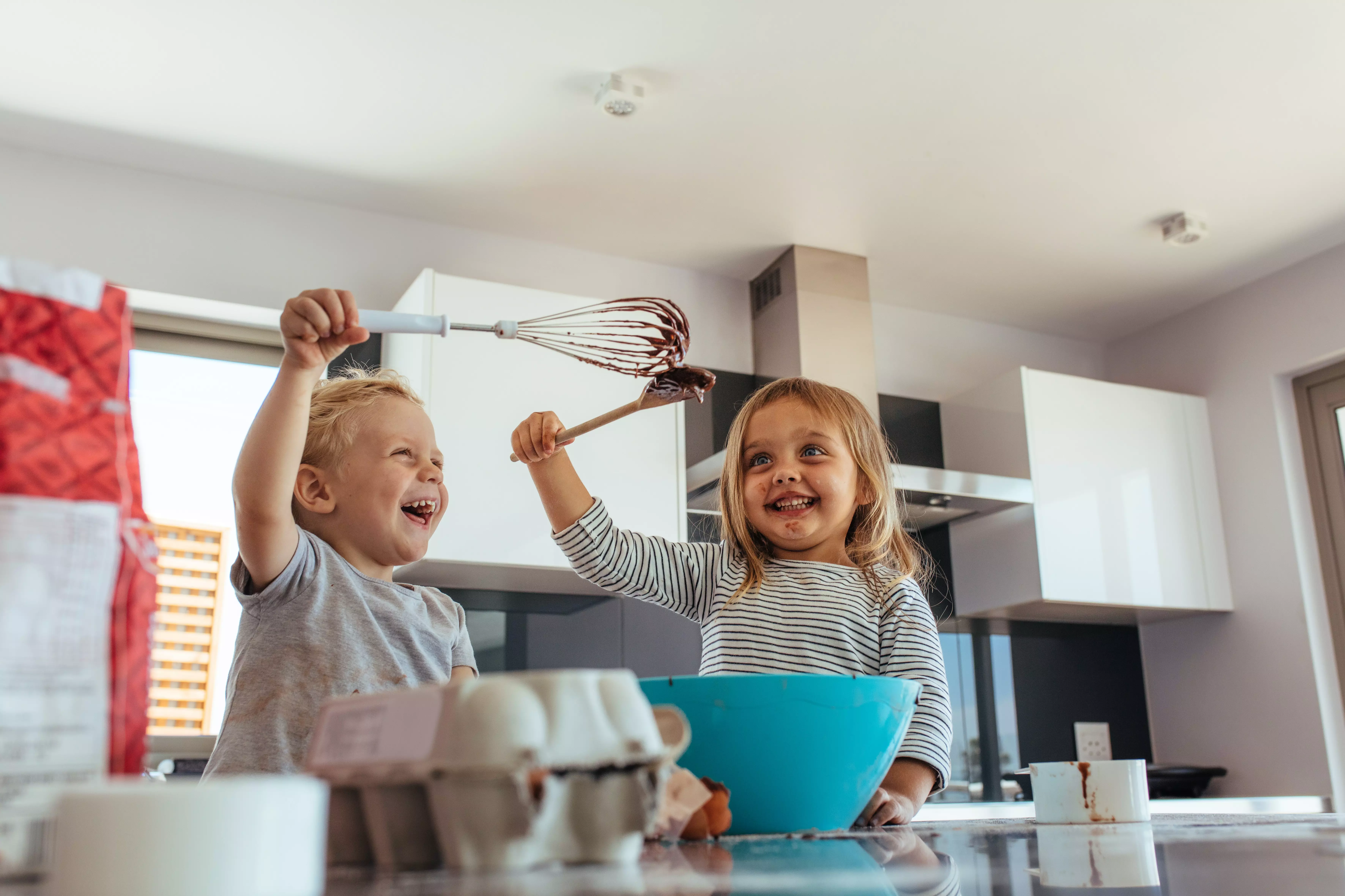 Léif klenge Jong a Meedchen kämpfen mat Whisk a Spatel wärend de Batter an enger Schossel vermëschen. Geschwëster enj...