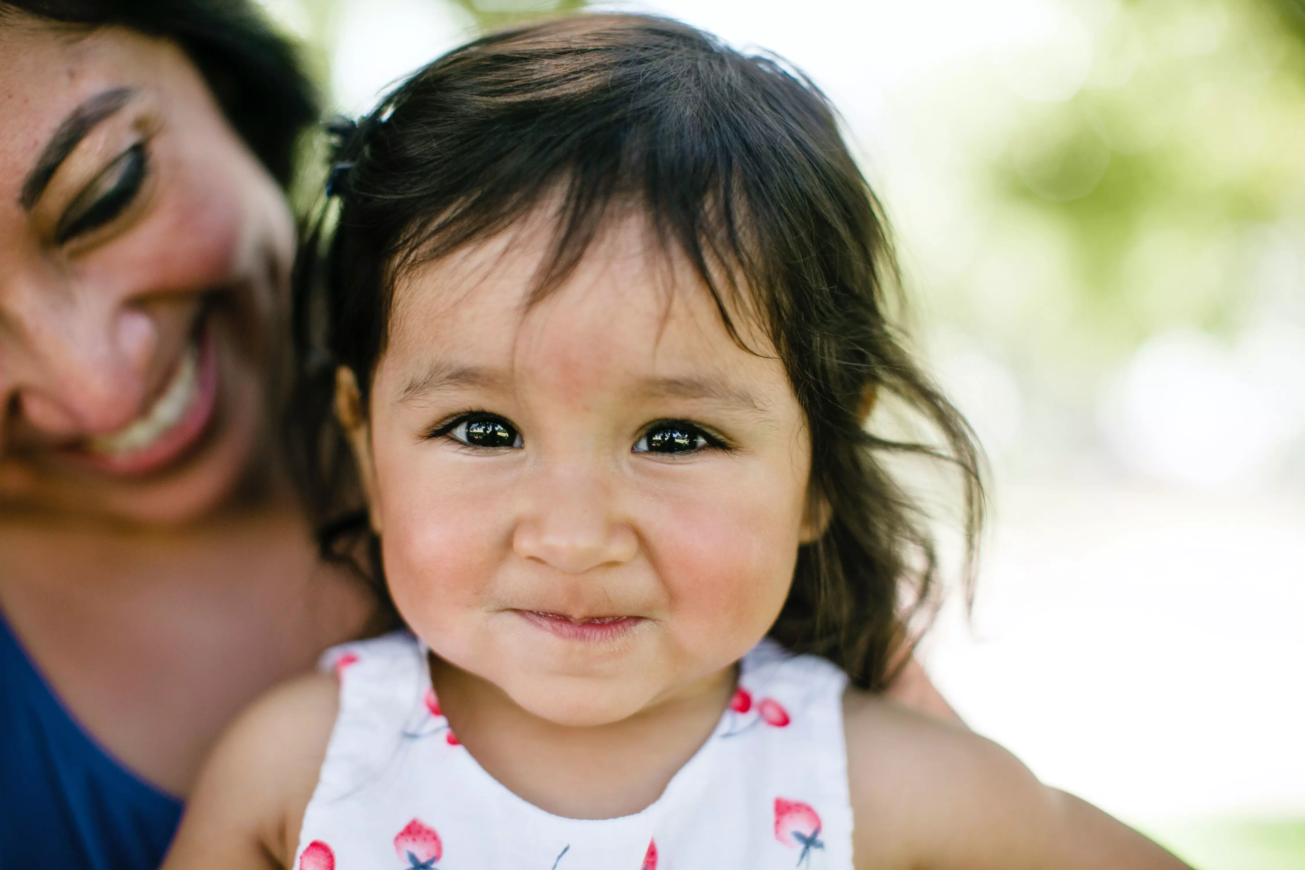 Close-up van ma en oulike donkerkop baba by die park, kort middelname vir meisies