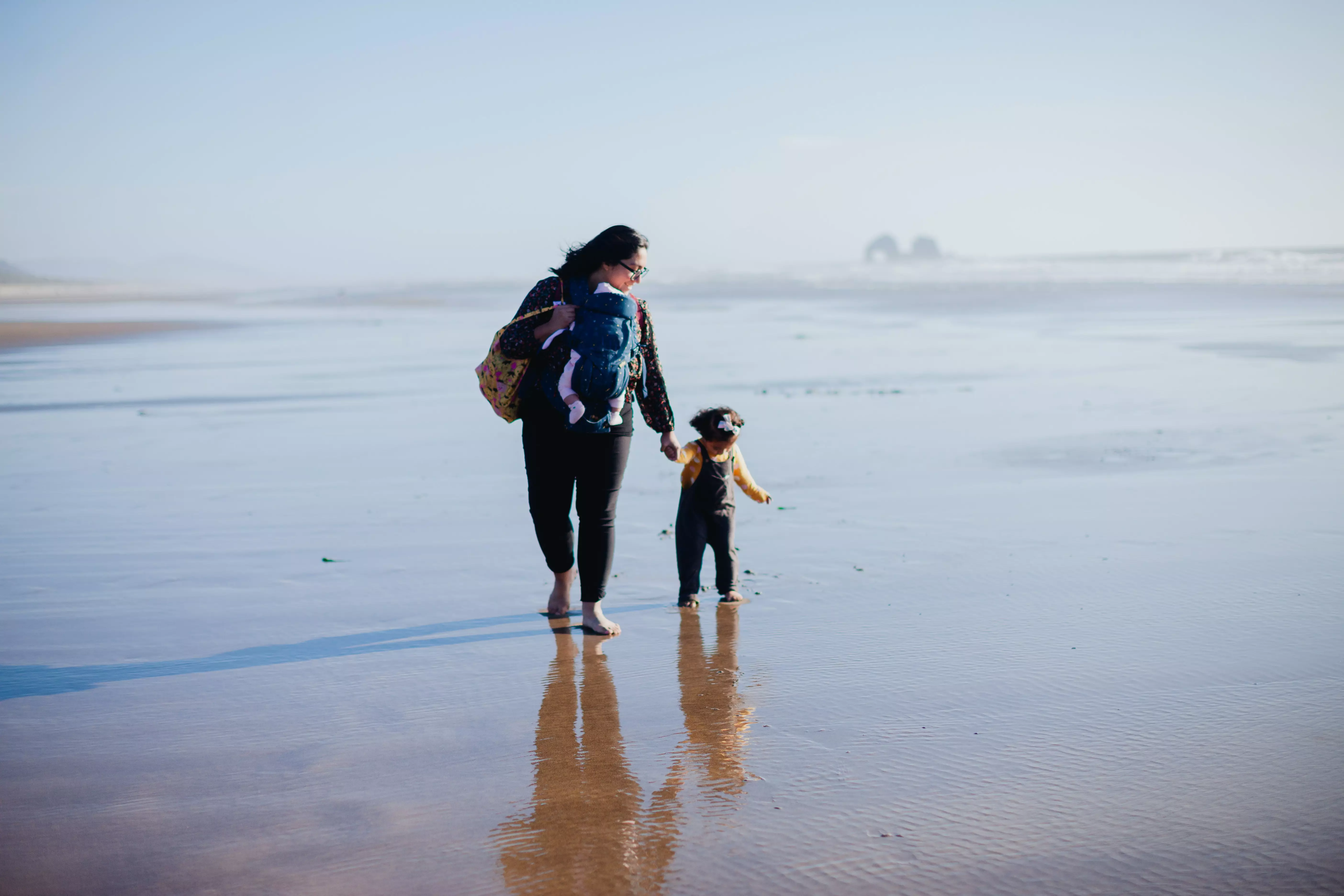 En vakker, lykkelig latinamerikansk familie som går på stranden sammen: en mor og hennes to barn. En ...