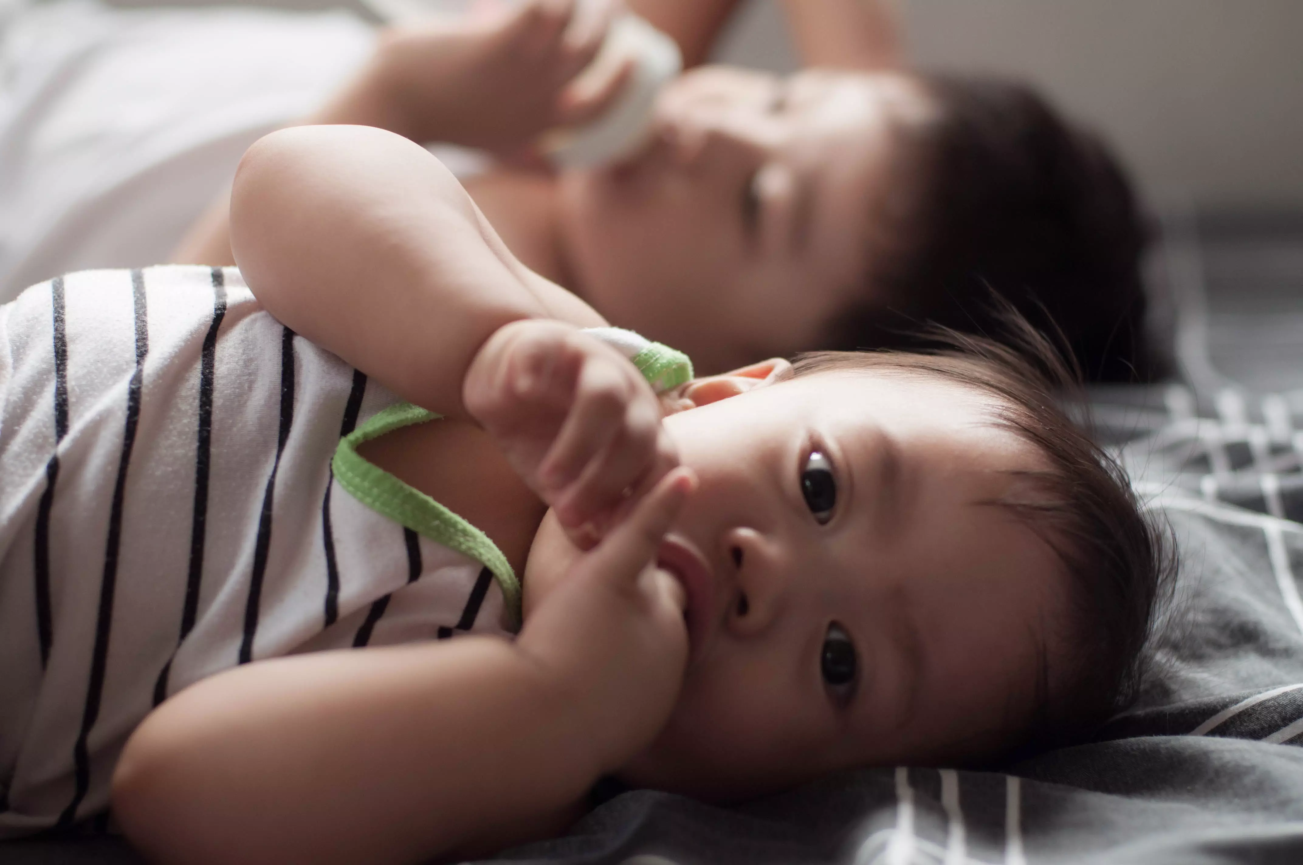 Opregte portret van Suidoos-Asiatiese babaseuns wat saam melk drink terwyl hulle lê ...